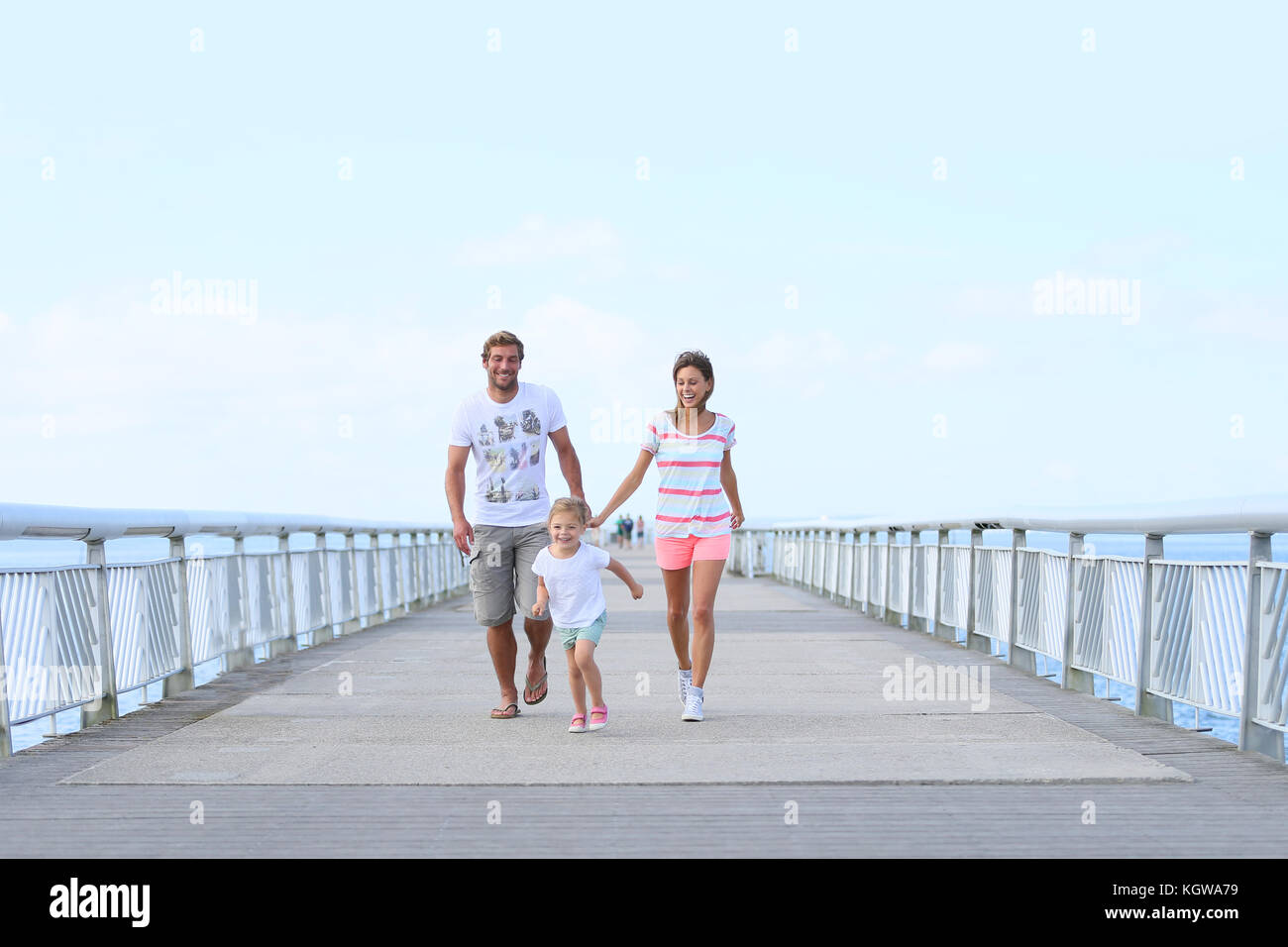 Little girl with parents running on a bridge Stock Photo - Alamy