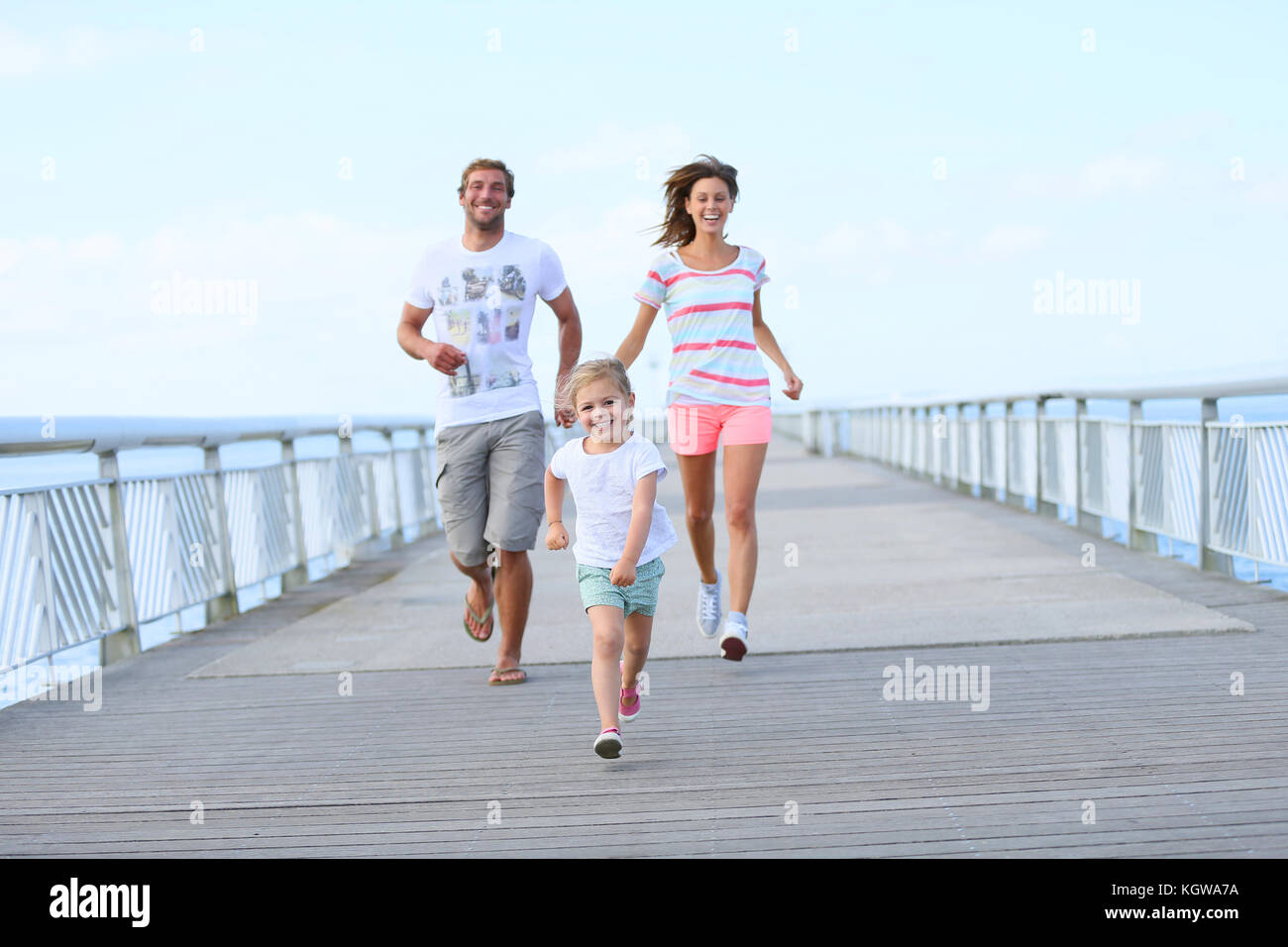 Little girl with parents running on a bridge Stock Photo - Alamy