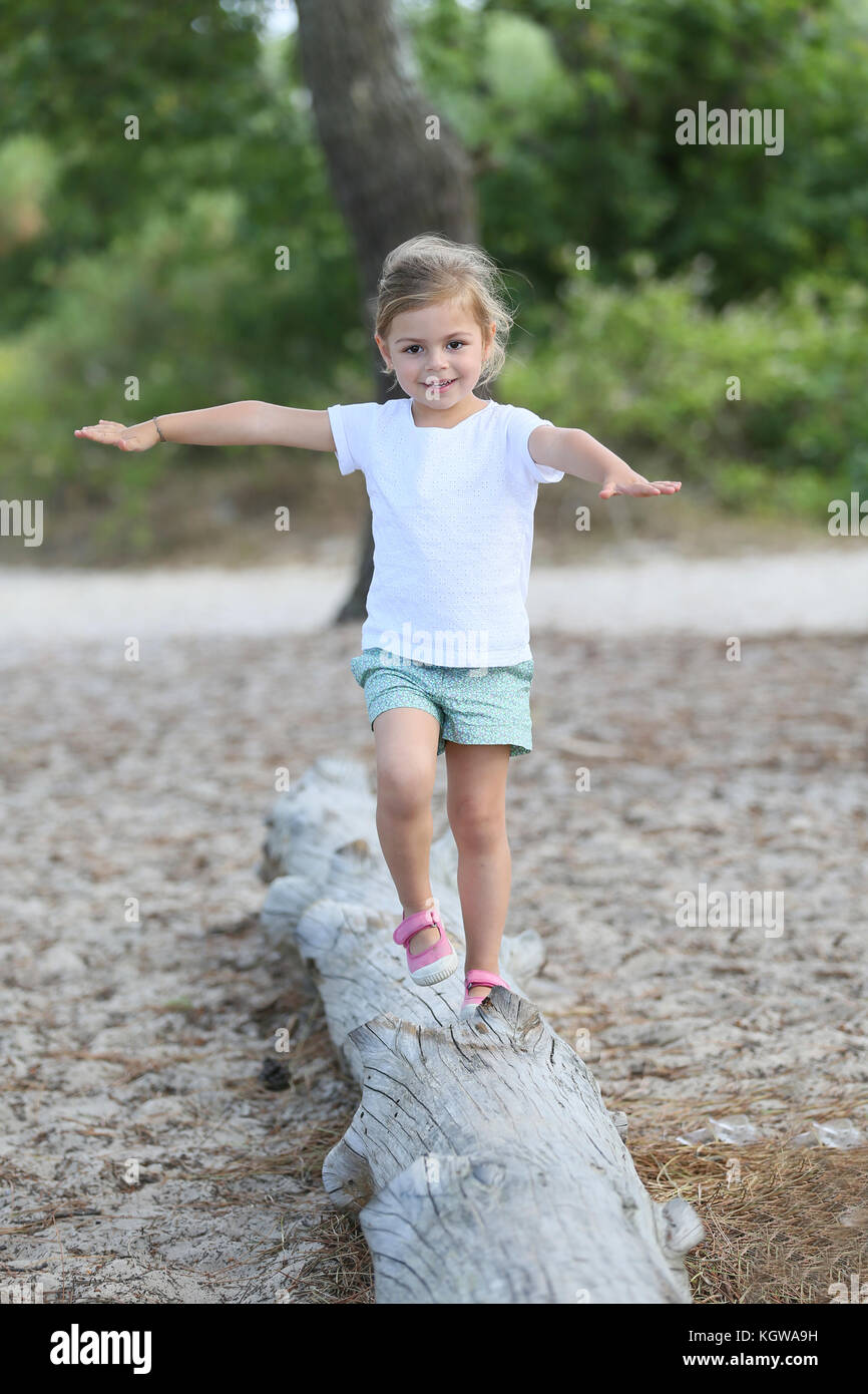 Little girl walking on tree trunk in forest Stock Photo - Alamy