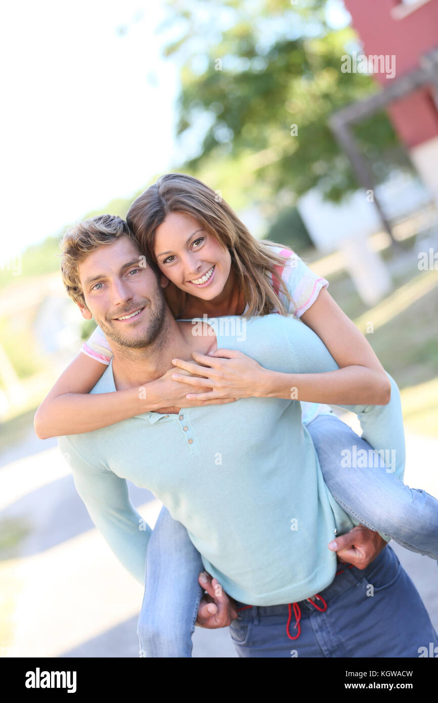 Man giving piggyback ride to woman in front of new home Stock Photo - Alamy