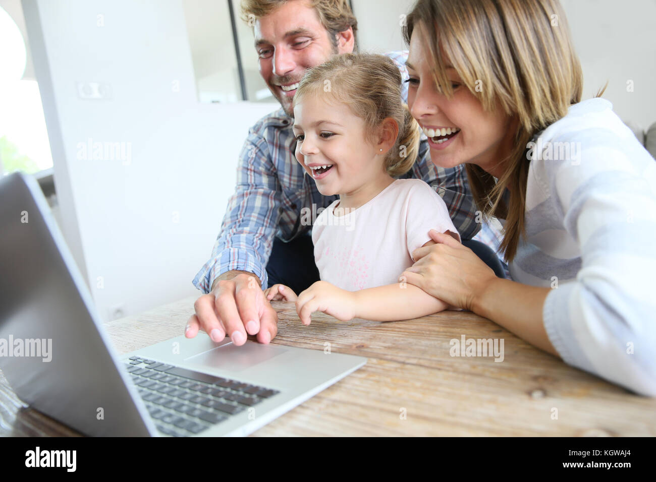 Parents with little girl laughing in front of laptop computer Stock ...