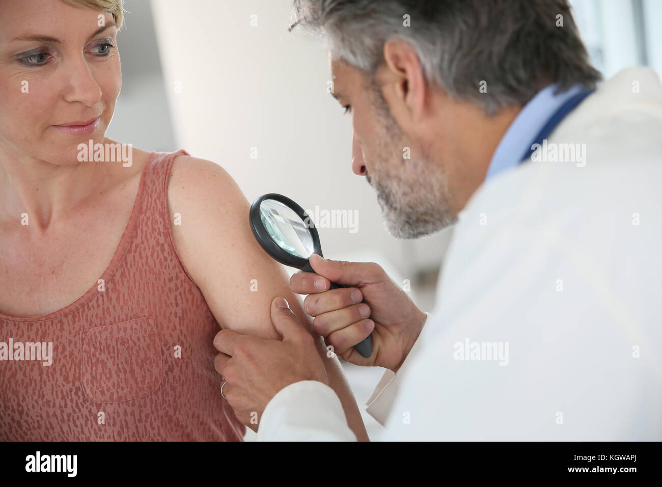 Dermatologist looking at woman's mole with magnifier Stock Photo - Alamy