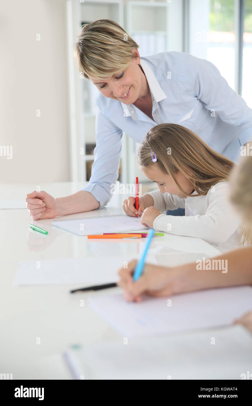Teacher helping kids in classroom Stock Photo - Alamy