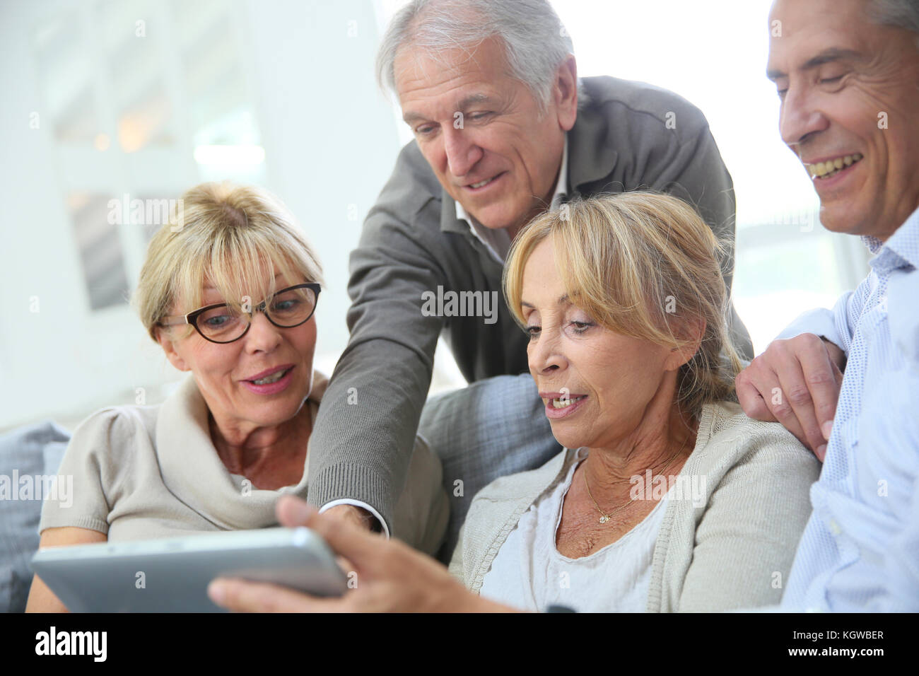 Group of retired people sitting in sofa and using tablet Stock Photo ...