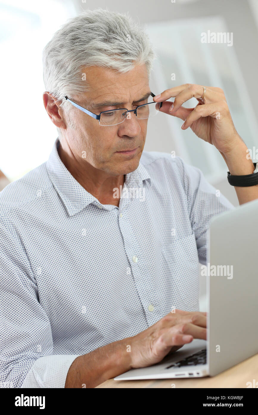 Senior man with eyeglasses using laptop computer Stock Photo - Alamy