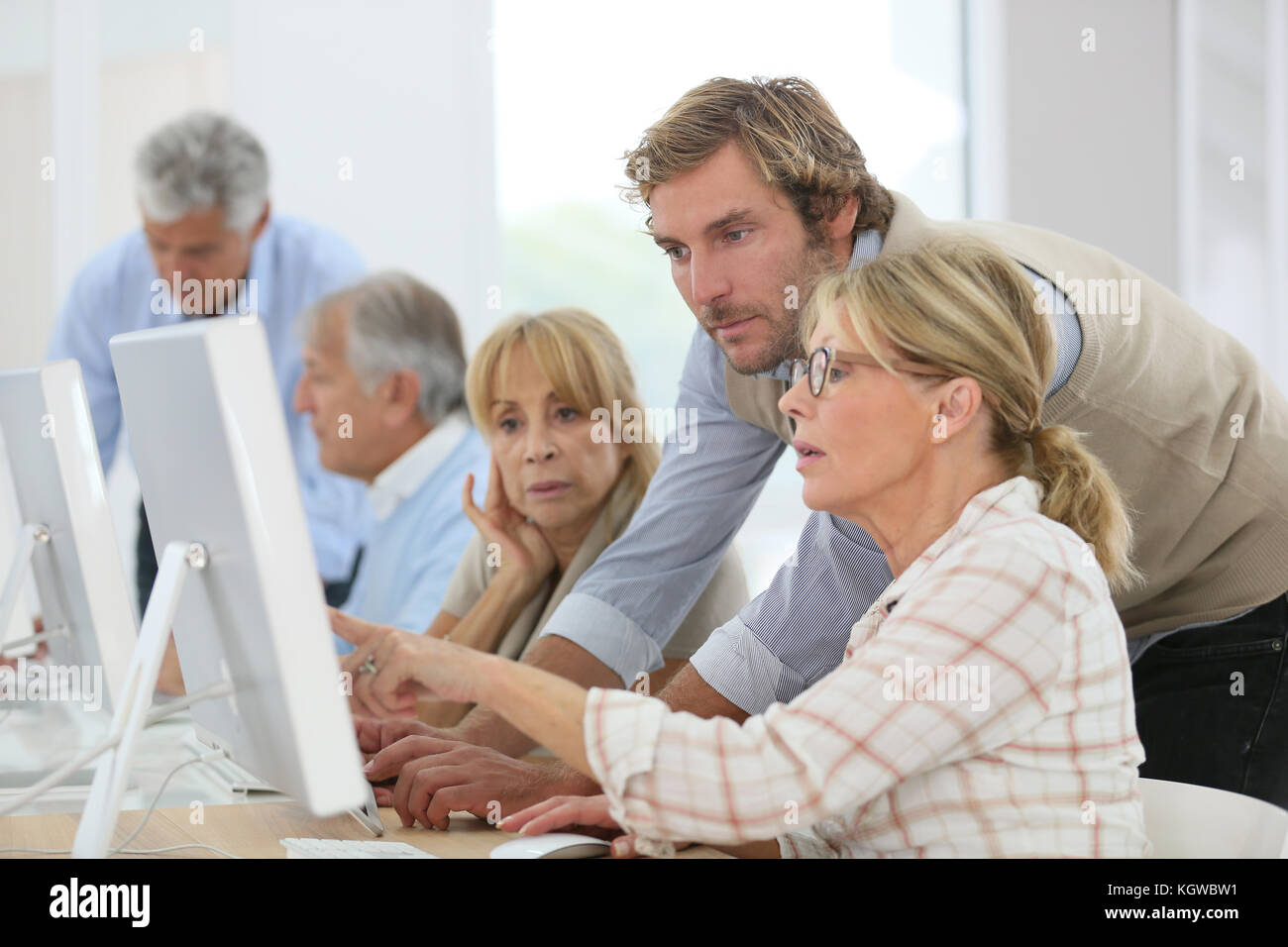 Instructor helping senior woman in computing class Stock Photo - Alamy