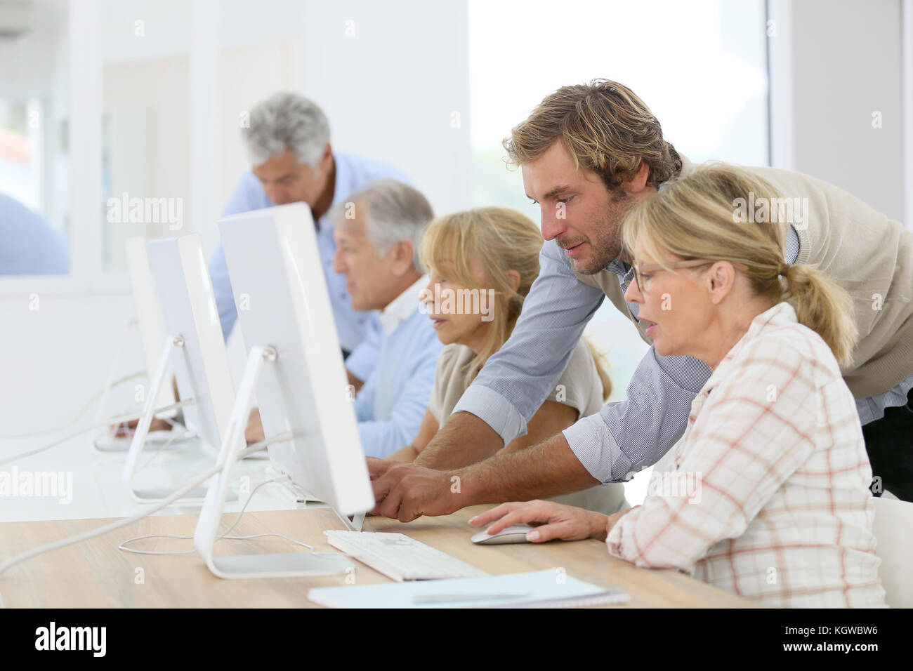 Instructor helping senior woman in computing class Stock Photo - Alamy