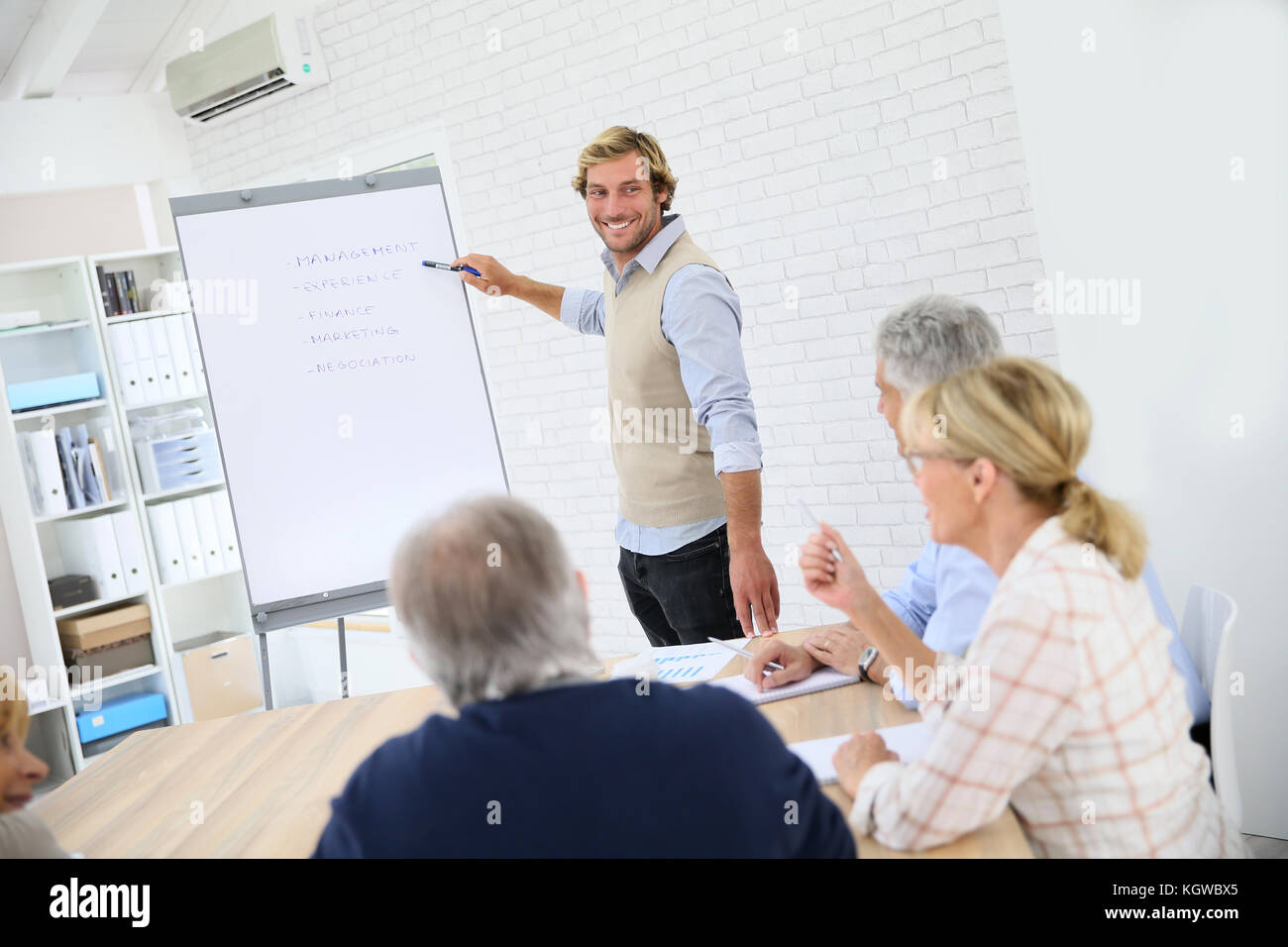 Business instructor leading meeting with senior training group Stock ...