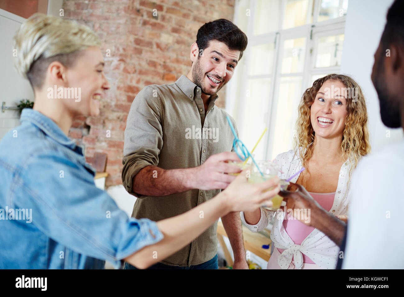 Ecstatic friends cheering with cocktails at home party and enjoying ...