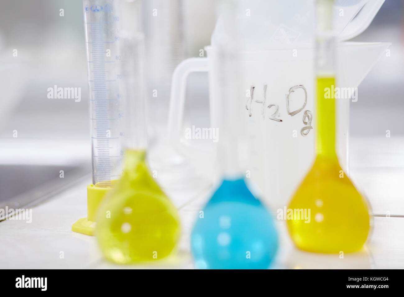 Yellow and blue liquids in tubes and container wih chemical compound ...