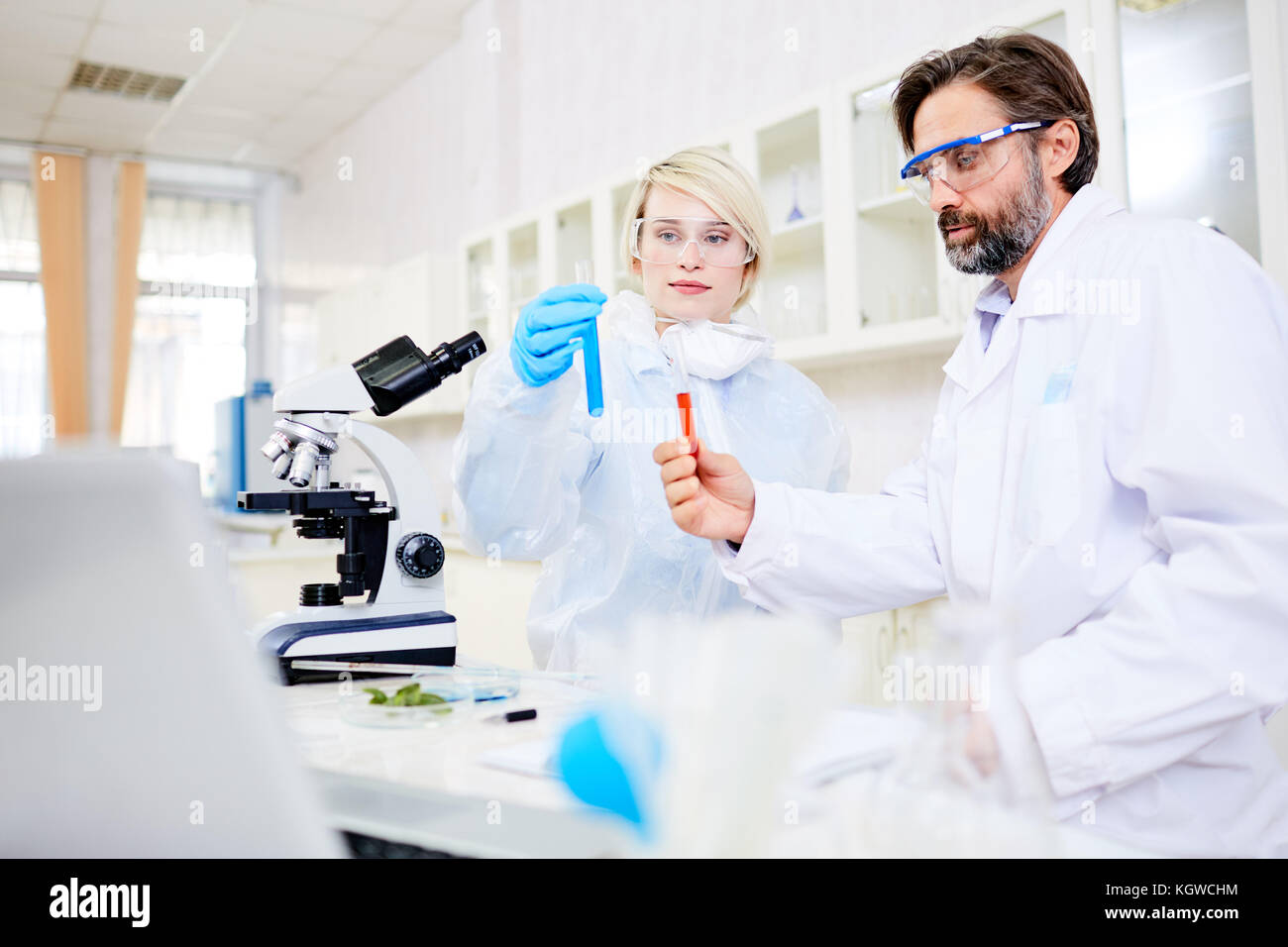 Scientific investigators comparing two fluids in flasks during ...