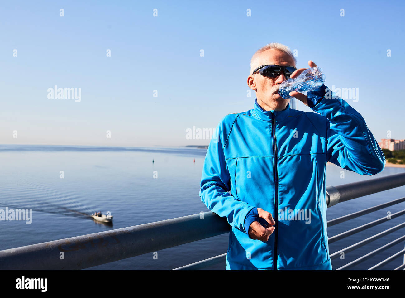 Sporty mature man drinking fresh water from plastic bottle after ...