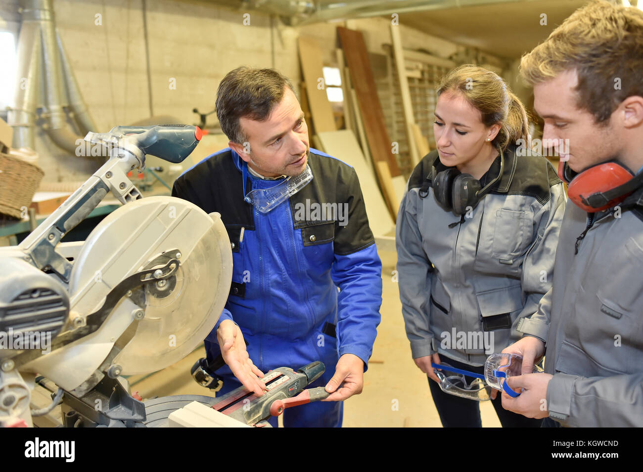 Carpentry teacher showing sawing machine to students Stock Photo - Alamy