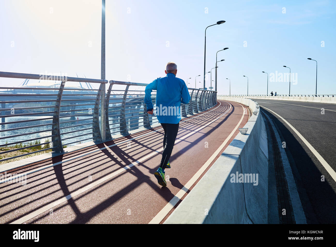 Active man running along riverside bridge in urban environment Stock ...