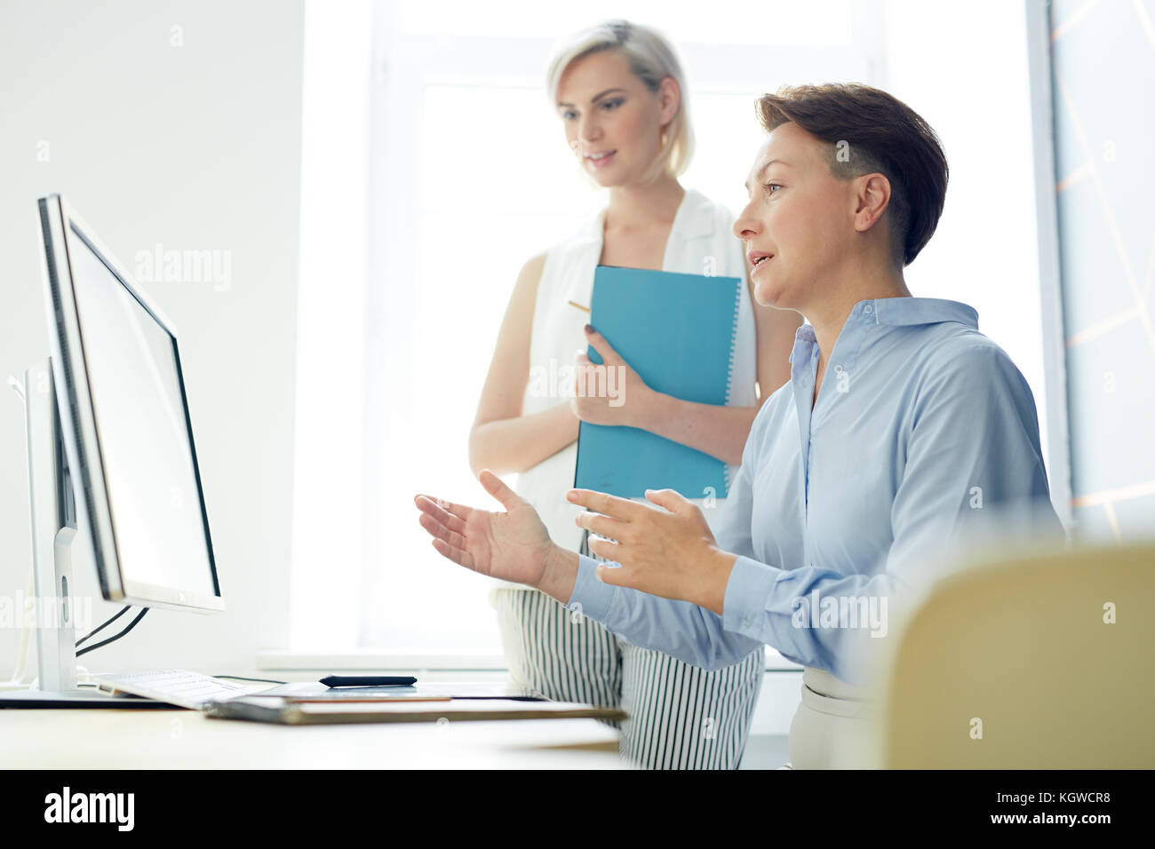 Businesswoman making presentation on computer display to her colleague ...