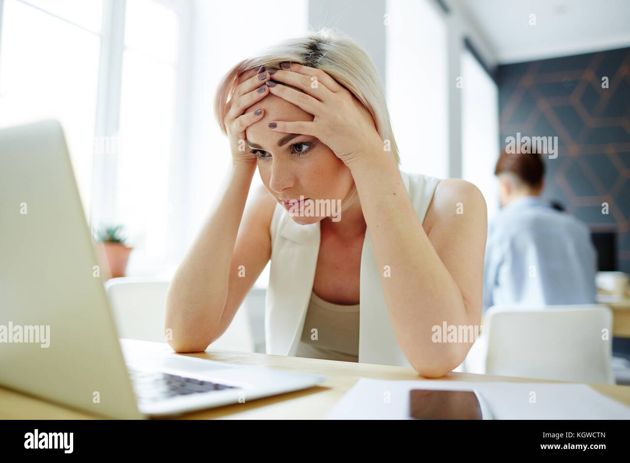 Tired manager sitting by workplace in front of laptop and working over ...