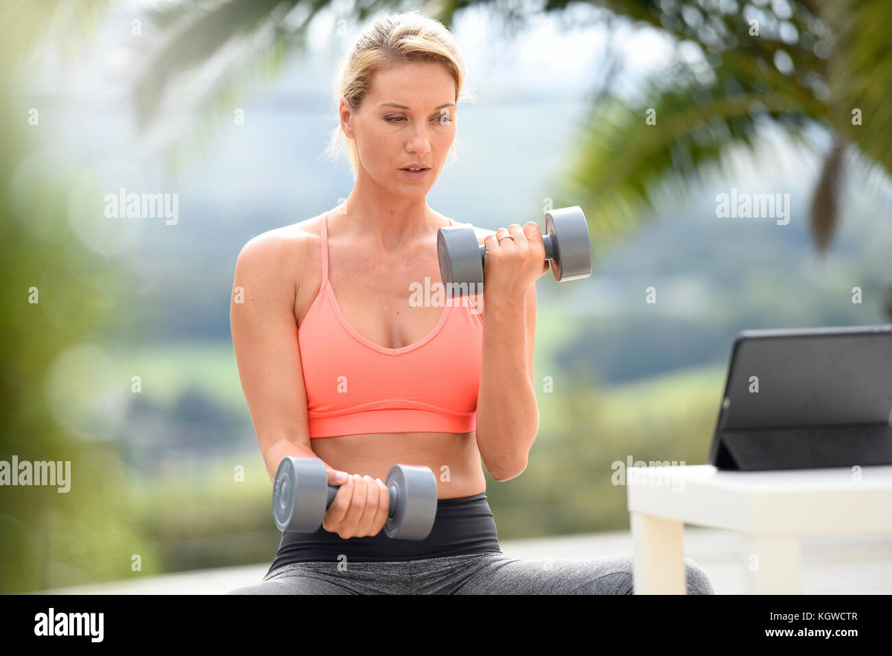 Fitness girl doing weight exercises in front of tablet Stock Photo - Alamy