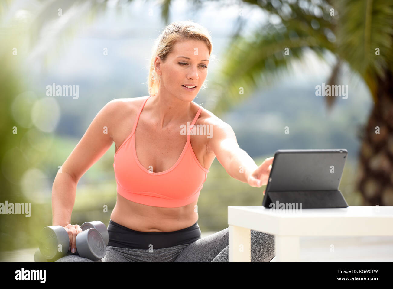 Fitness girl doing weight exercises in front of tablet Stock Photo - Alamy
