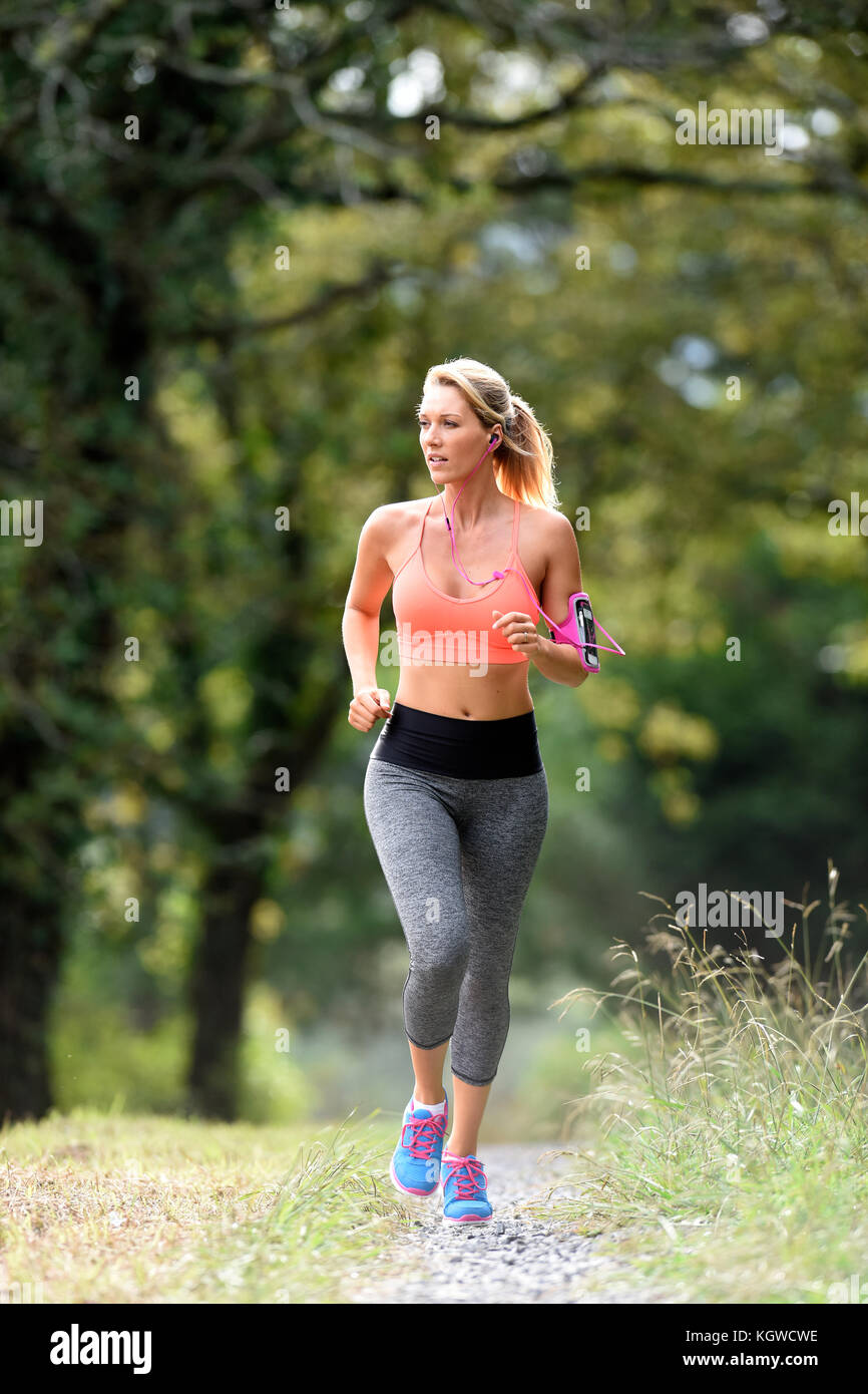 Beautiful athletic woman running in forest Stock Photo - Alamy