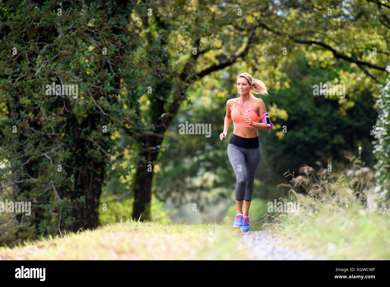 Beautiful athletic woman running in forest Stock Photo - Alamy