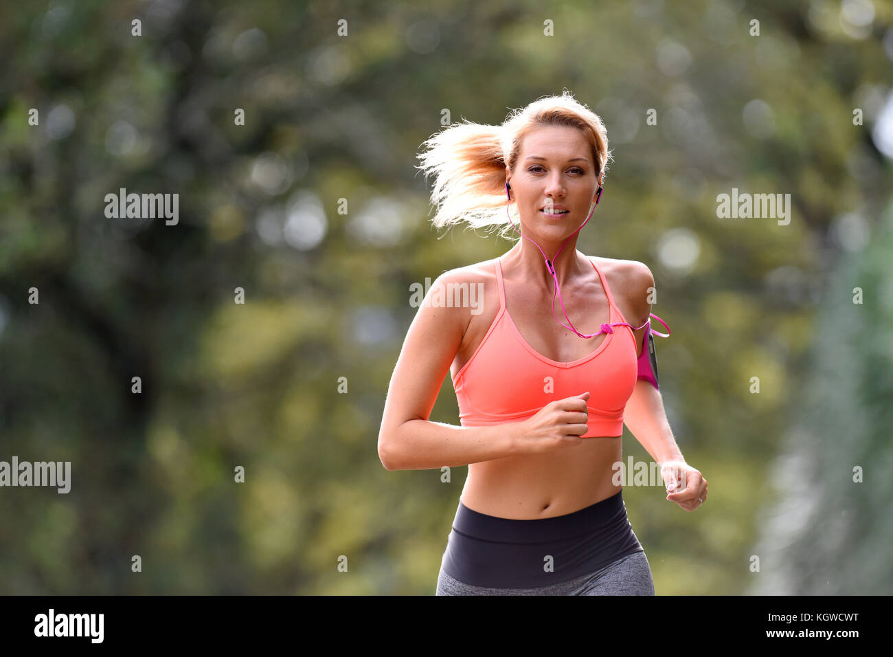 Beautiful athletic woman running in forest Stock Photo - Alamy