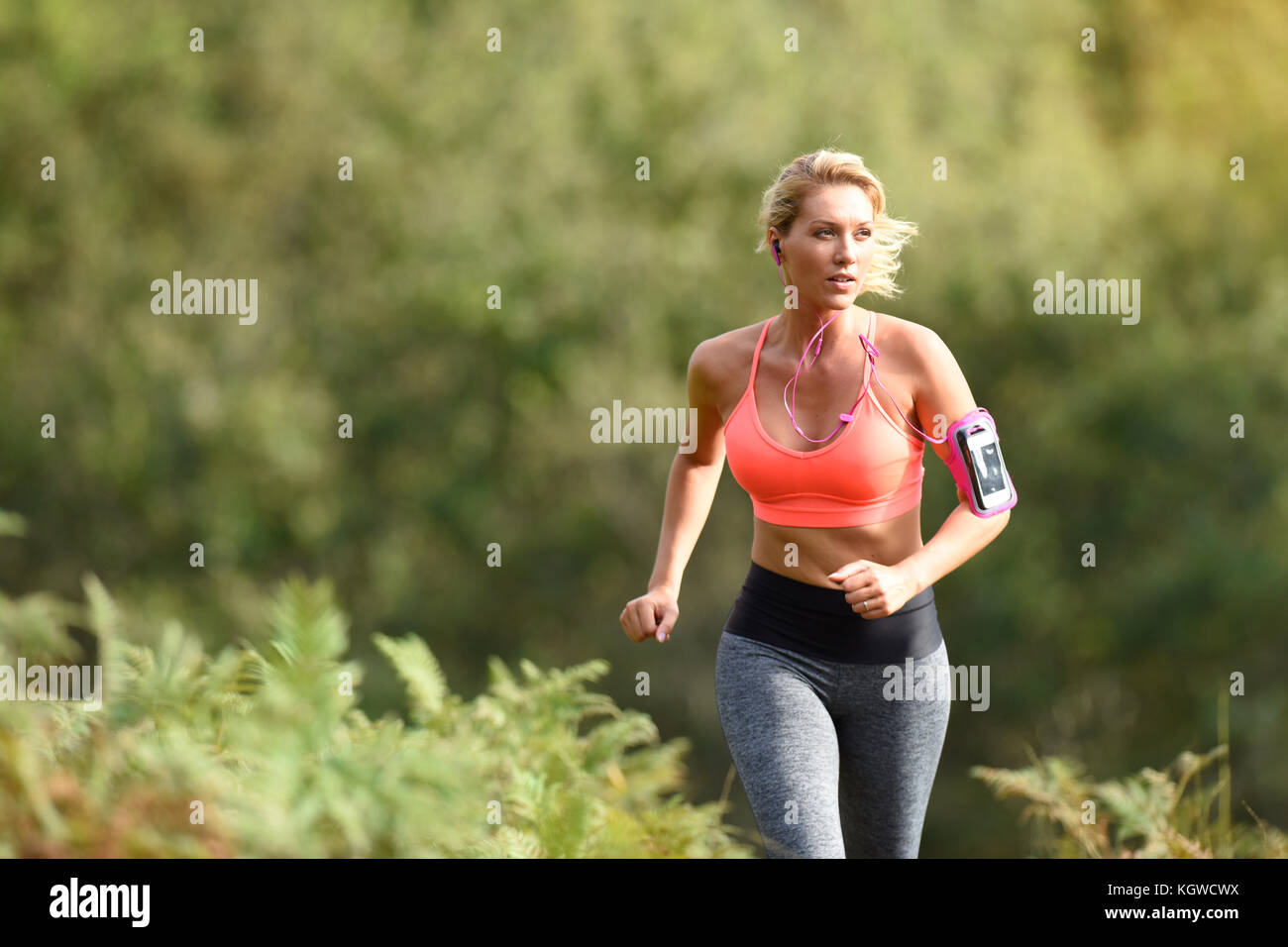 Beautiful athletic woman running in forest Stock Photo - Alamy