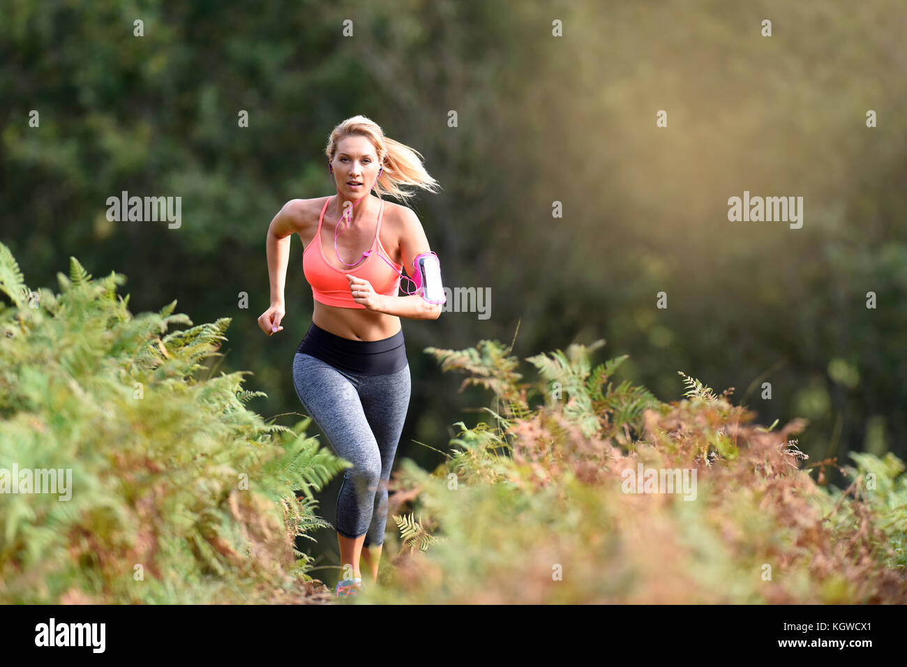 Beautiful athletic woman running in forest Stock Photo - Alamy