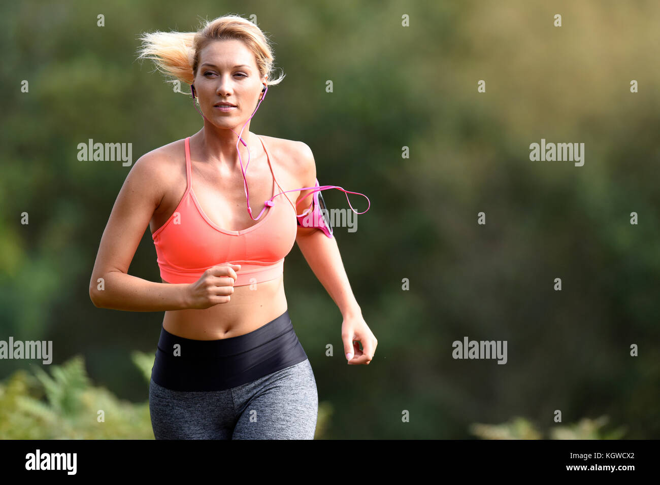 Beautiful athletic woman running in forest Stock Photo - Alamy