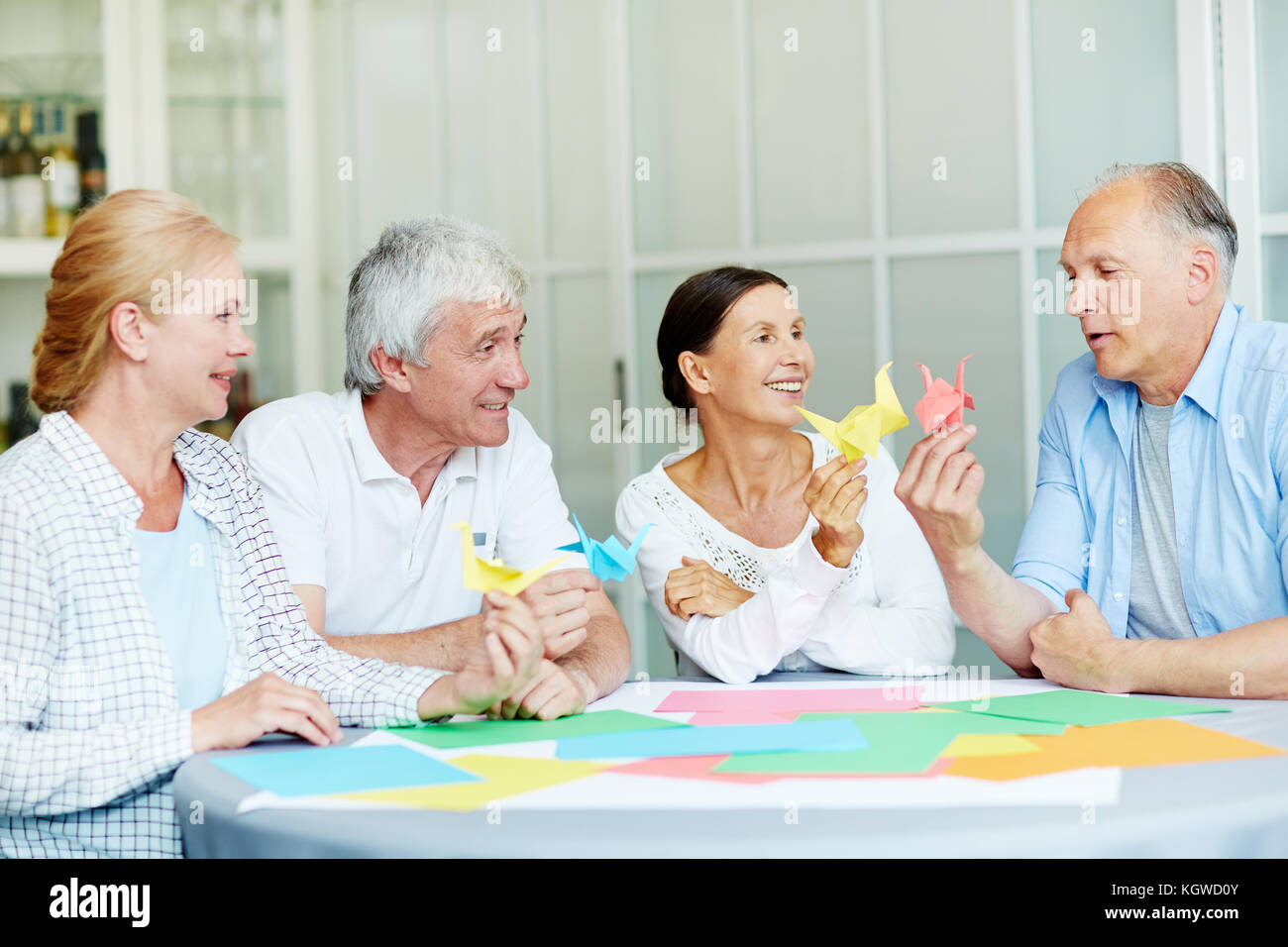 Senior friends bragging with self-made colorful paper figures and ...