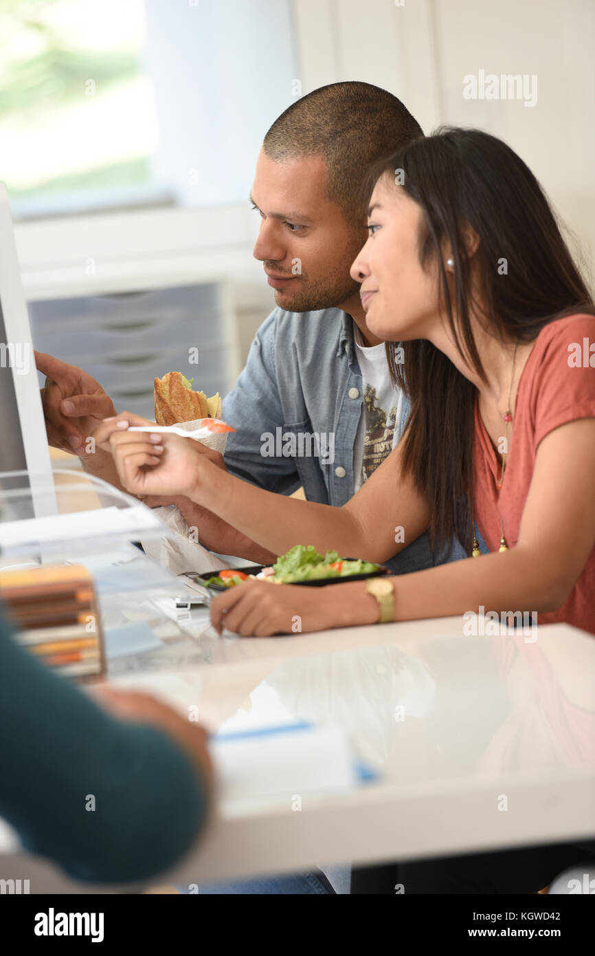 Office-workers having lunch in office in front of desktop Stock Photo ...