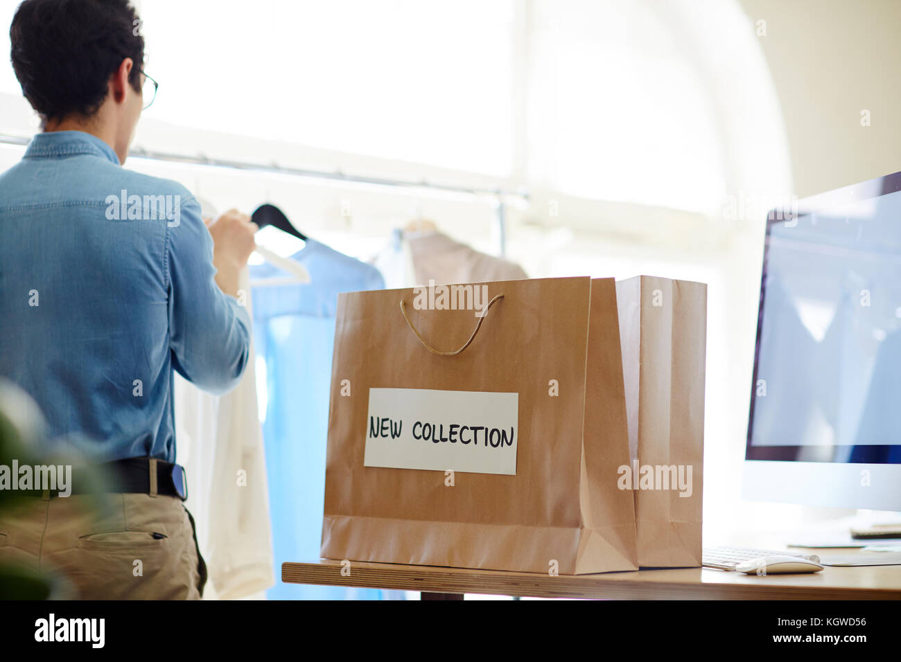 Rear view of clothes designer and paperbag with new collection sticker ...
