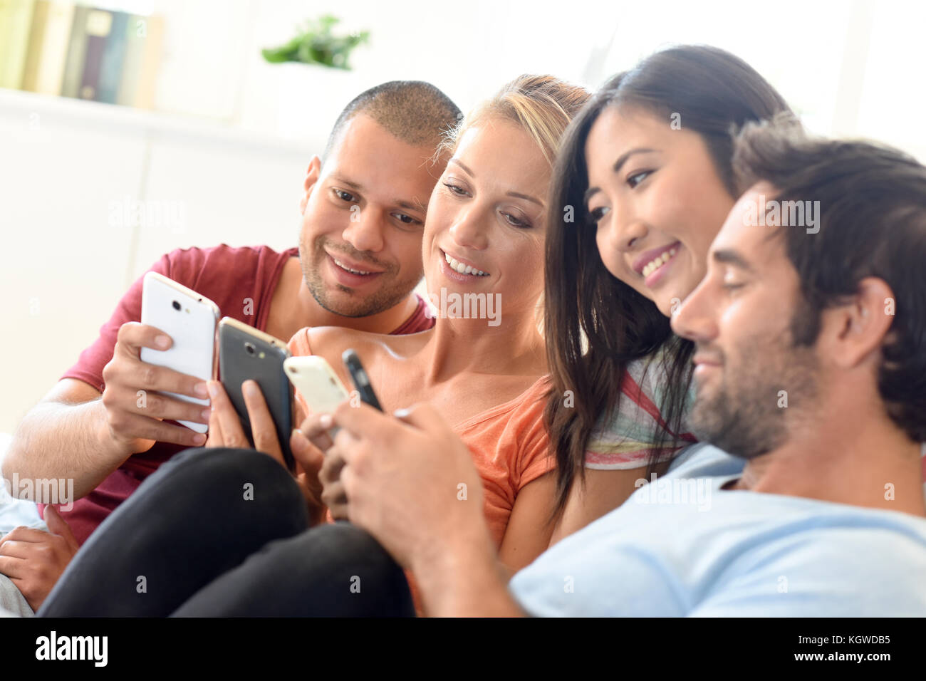 Friends at home playing with smartphones, connecting people Stock Photo ...
