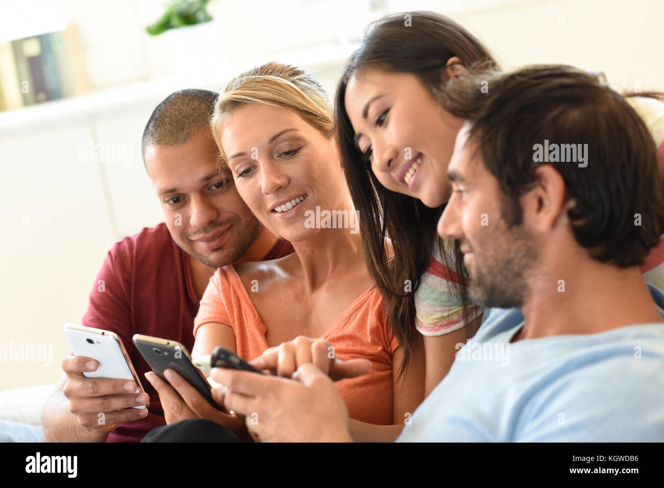 Friends at home playing with smartphones, connecting people Stock Photo ...