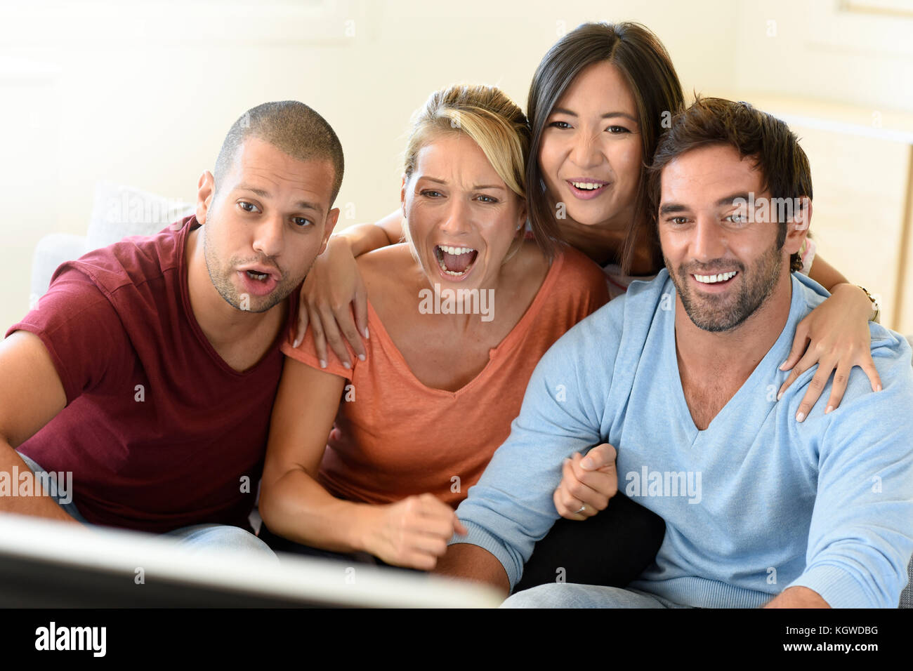 Friends in front of TV watching game Stock Photo - Alamy