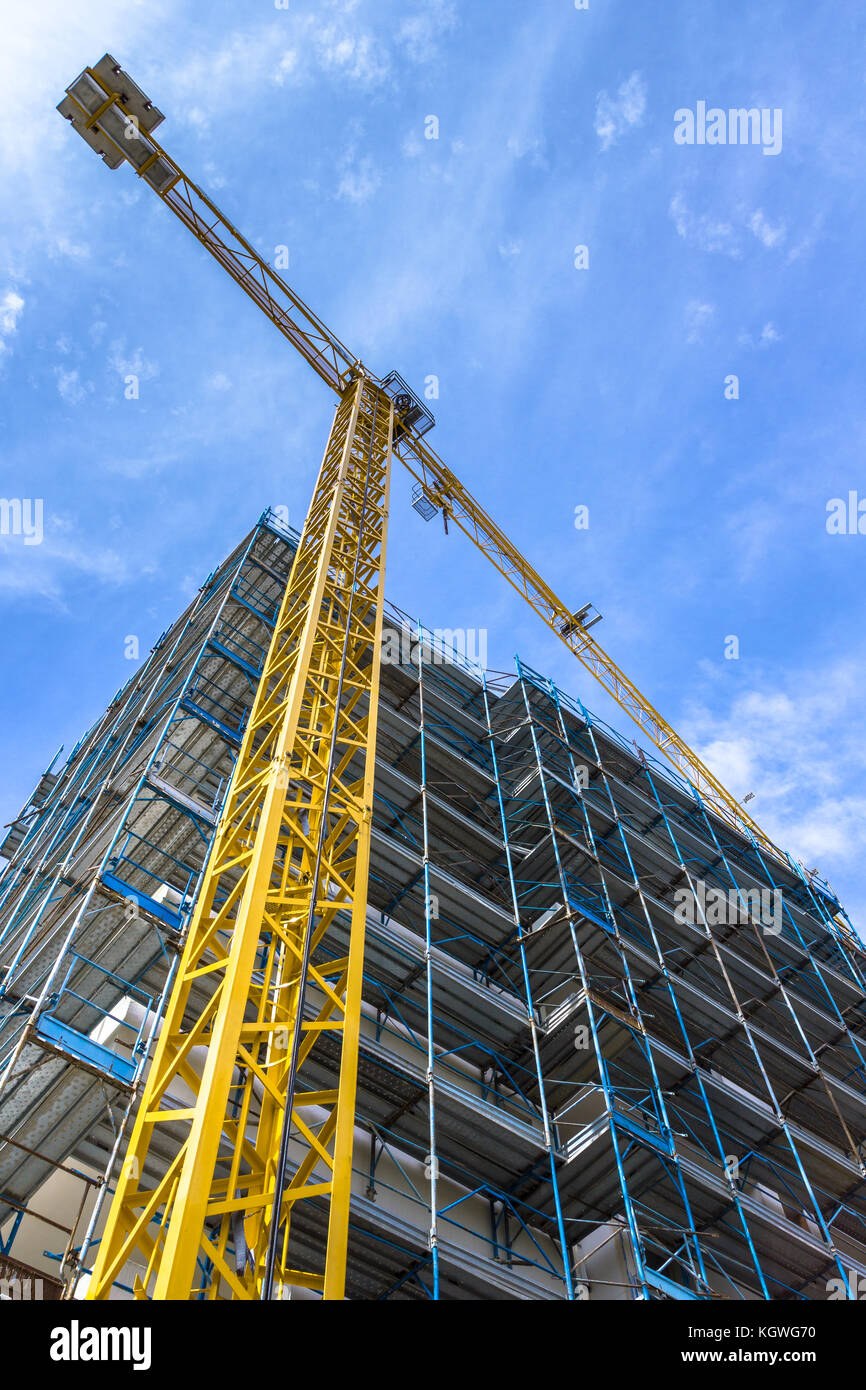 Construction site with yellow crane on sky background. Bottom view ...