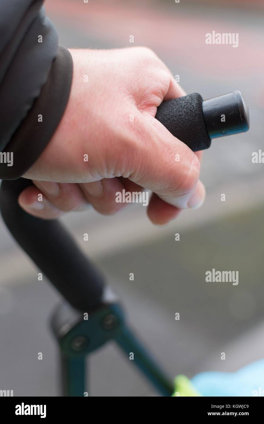 Male hand holding a blue colored pram stroller handle. Parent father ...