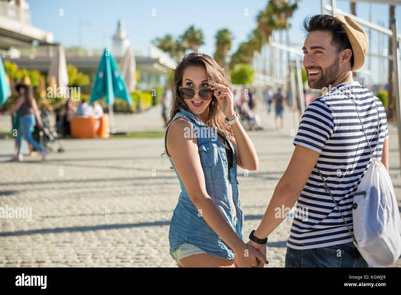 Portrait of happy couple holding hands walking on promenade Stock Photo ...