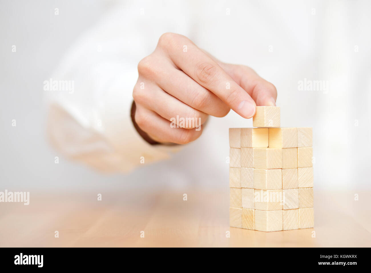 Man's hand adding the last missing wooden block into place. Business ...