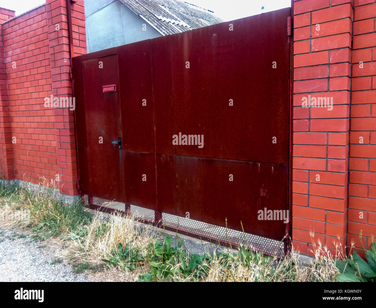 Steel rusty gates and a red brick fence Stock Photo - Alamy