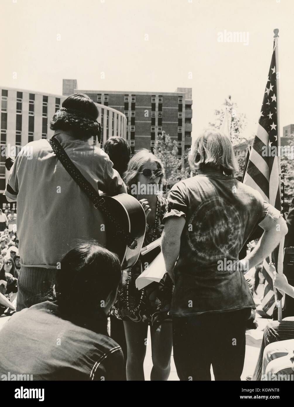 Student in hippie attire holding a guitar prepares to play for a large ...