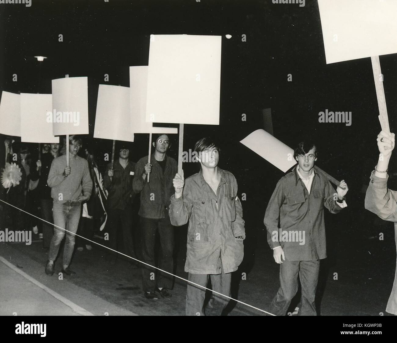 Students wearing hippie attire march at night carrying signs during an ...