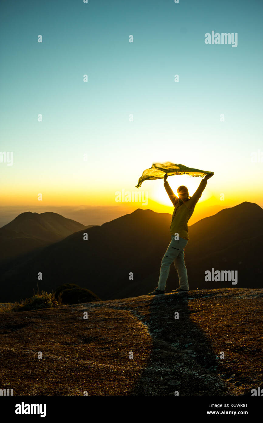 Happy Woman celebrating success on top of a mountain holding a piece of ...