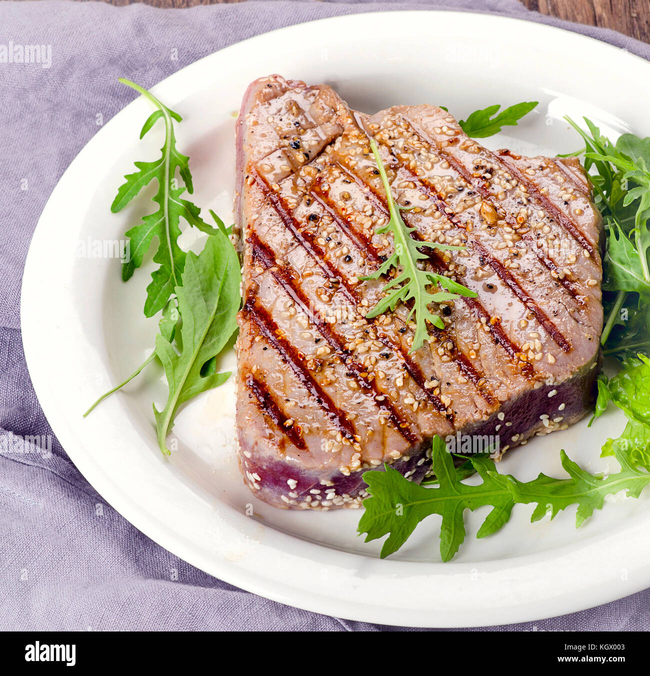 Grilled tuna fillet with fresh green salad leaves. View from above ...