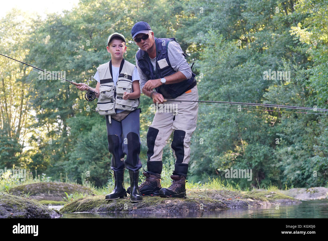 Dad with young boy fly-fishing in river Stock Photo - Alamy