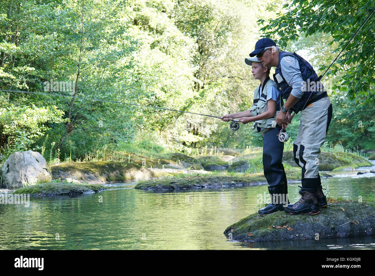 Dad with young boy fly-fishing in river Stock Photo - Alamy
