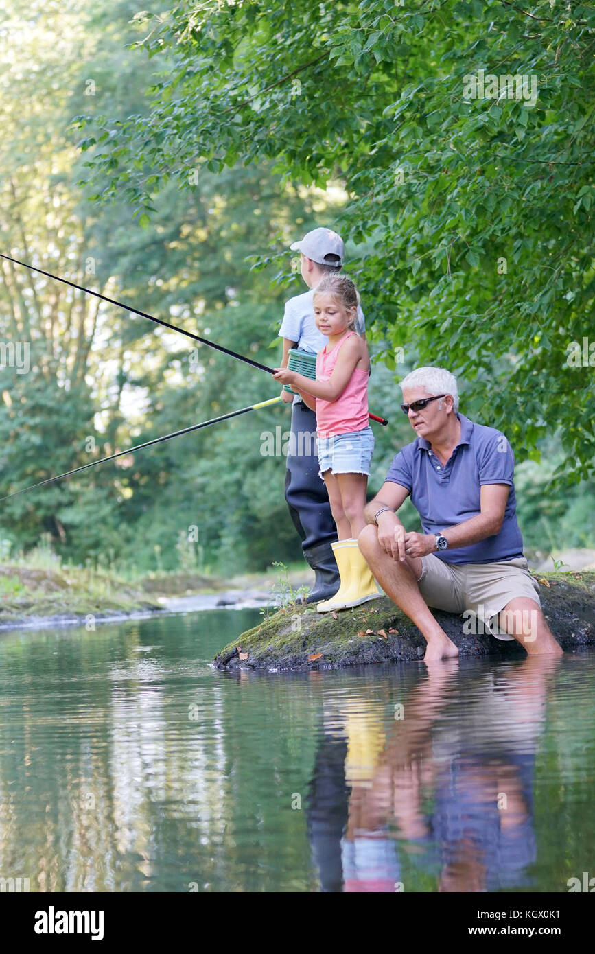 Dad teaching kids how to fish in river Stock Photo - Alamy