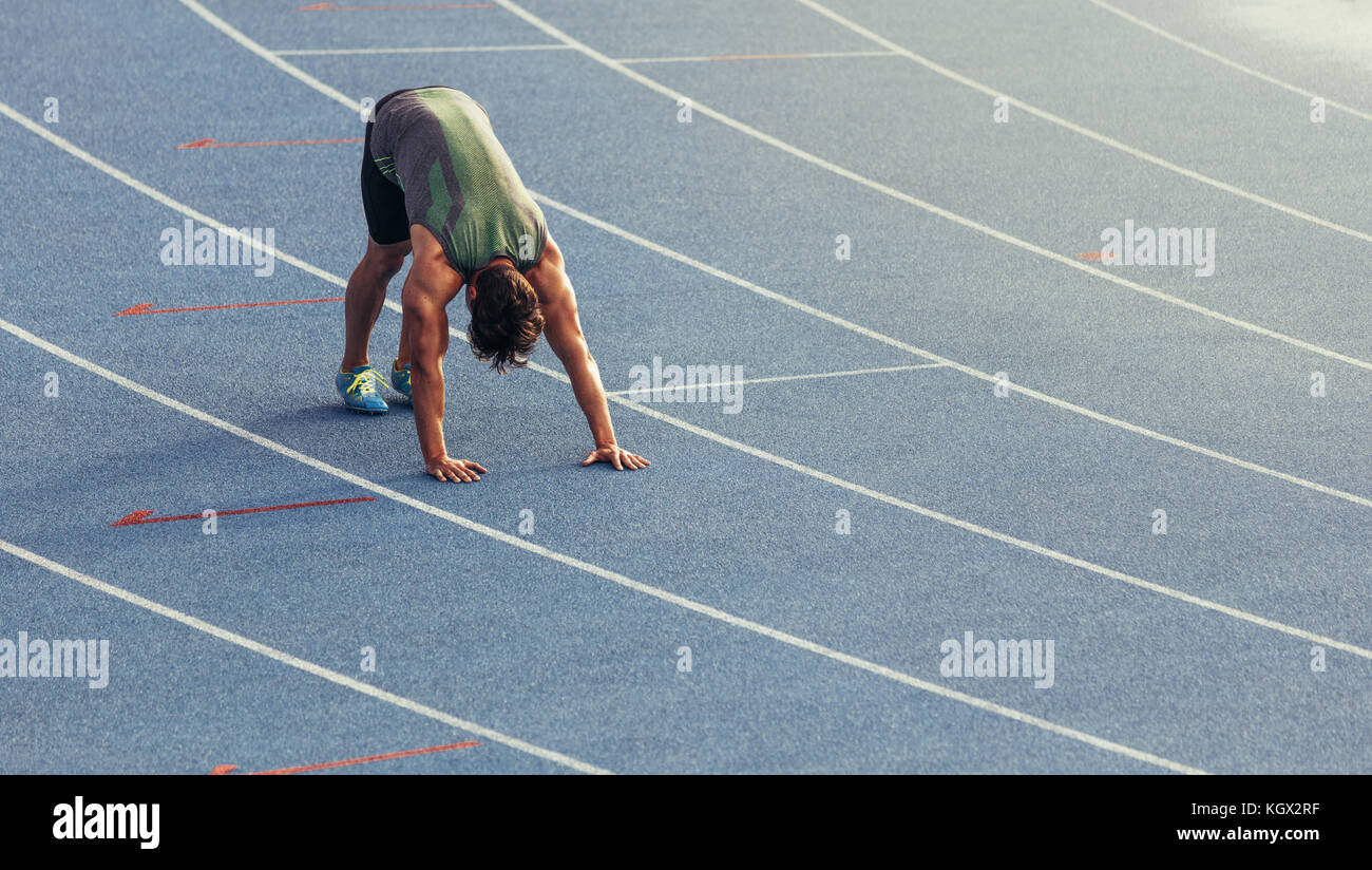 Athlete doing stretching exercises on the running track. Runner ...