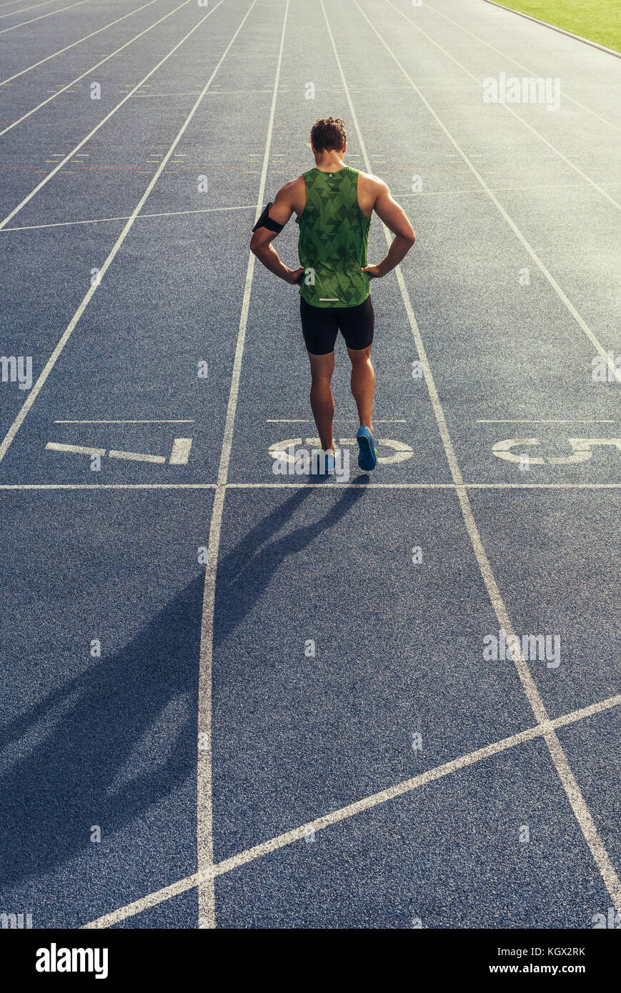 Rear view of an athlete standing on an all-weather running track ...
