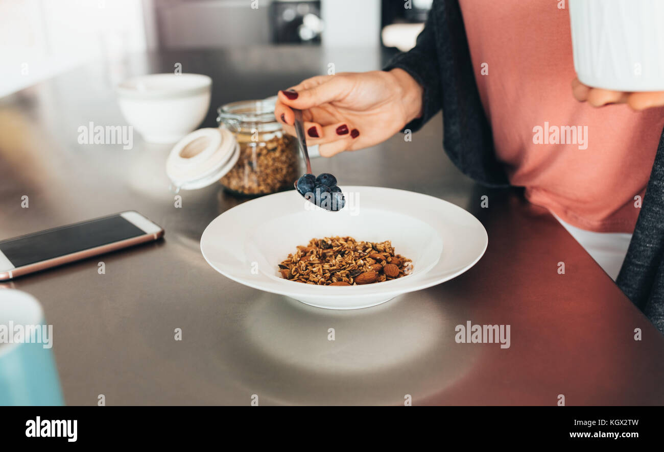 Woman preparing a healthy breakfast in her kitchen. Woman adding ...