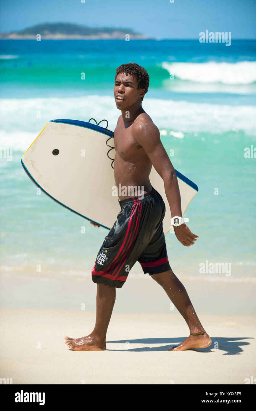 RIO DE JANEIRO - FEBRUARY 6, 2017: Young Brazilian surfer walks with ...